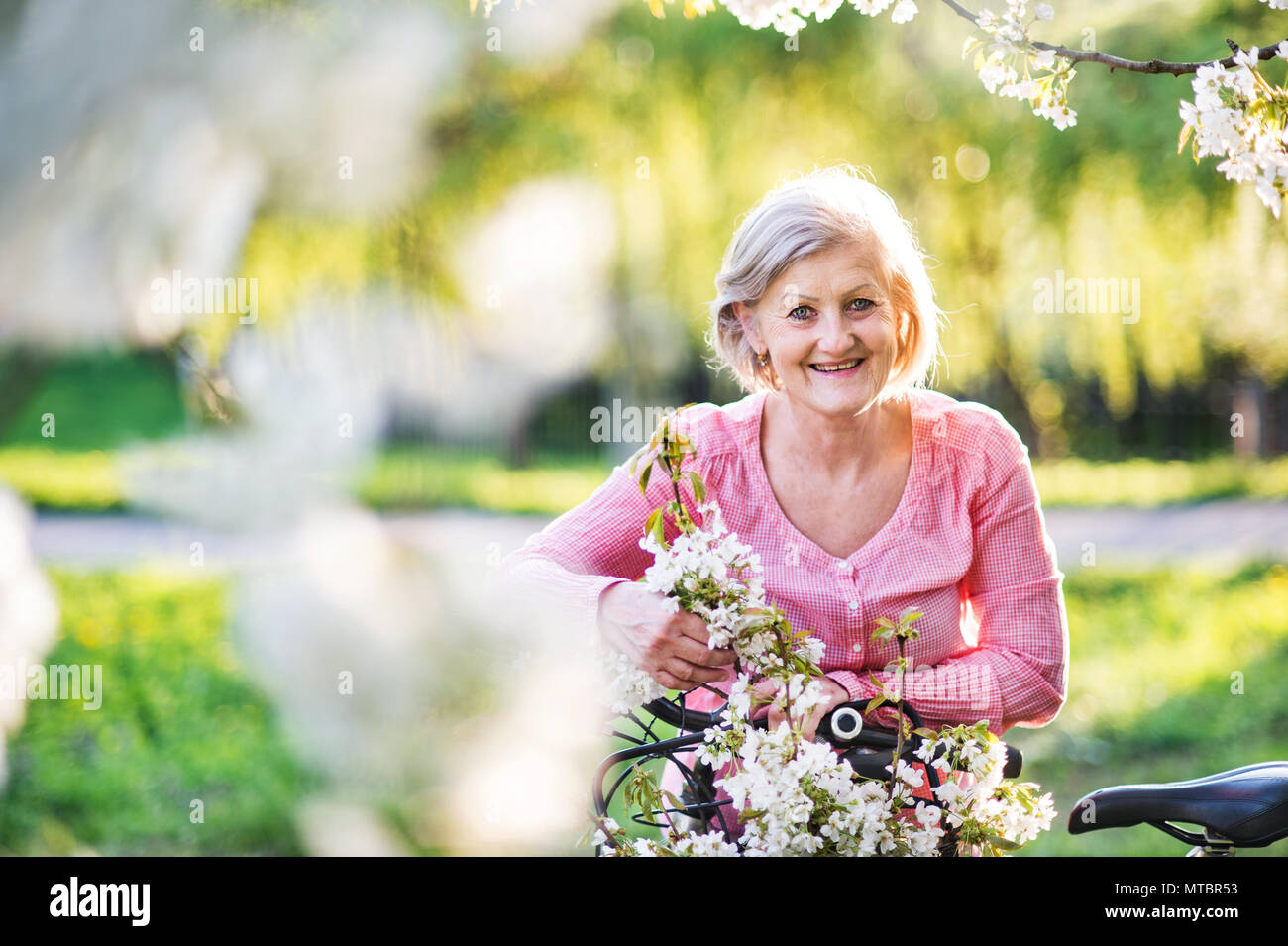 Beautiful senior woman with bicycle outside in spring nature Stock ...