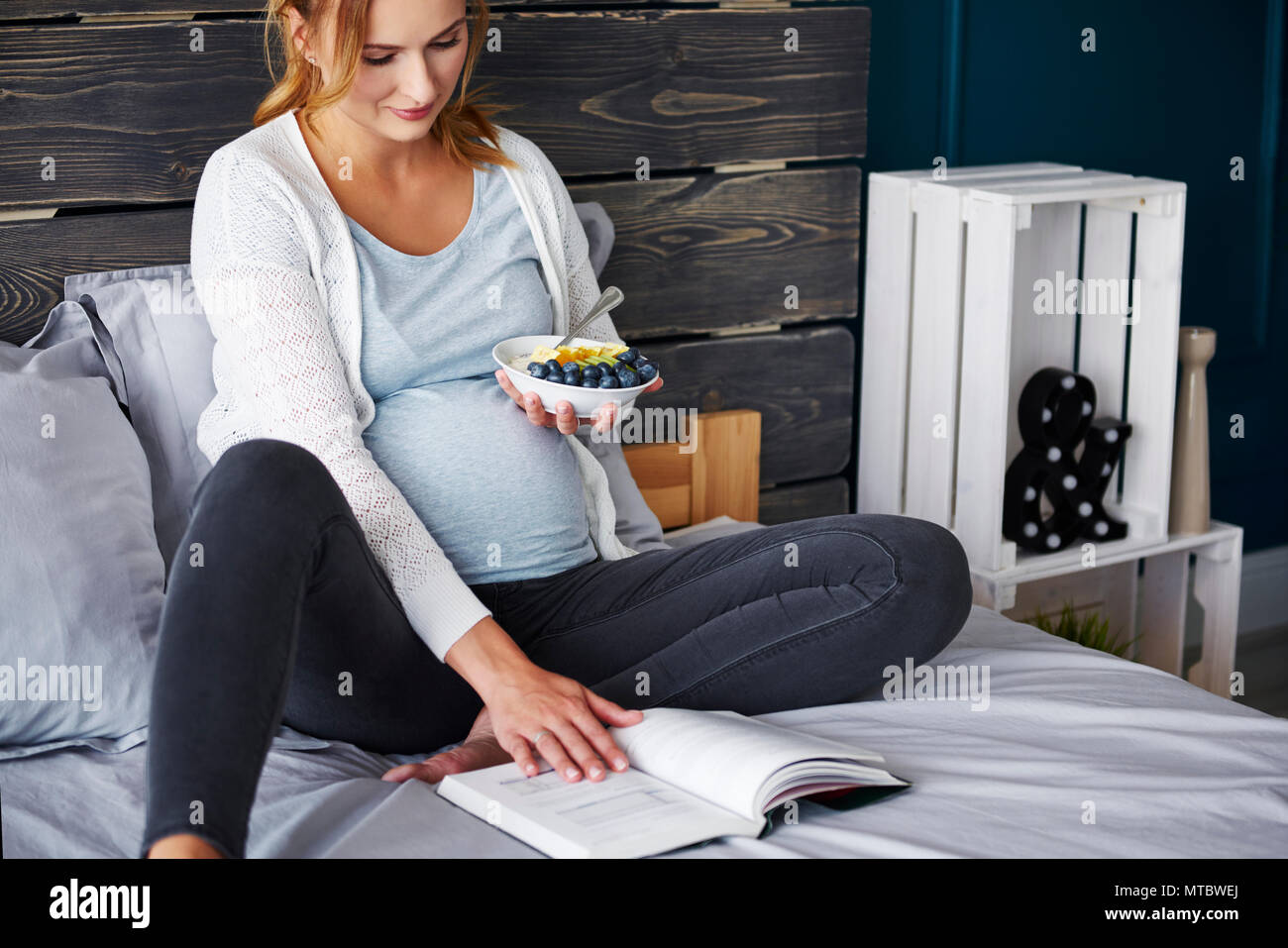 Pregnant woman eating and reading a book Stock Photo - Alamy