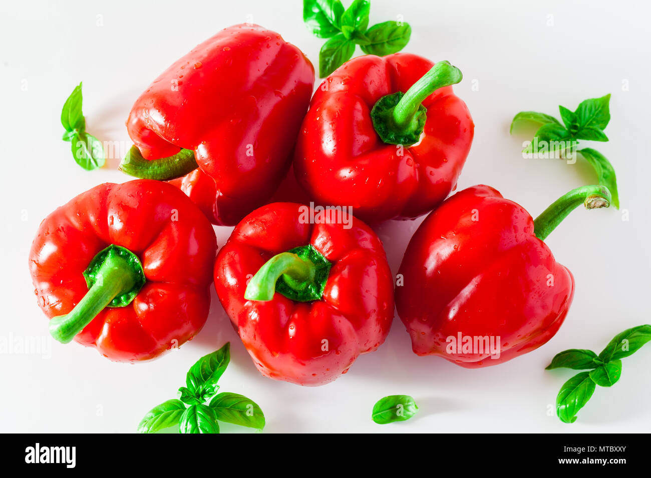 group of red ripe organic bell pepper and fresh basil leaves isolated ...