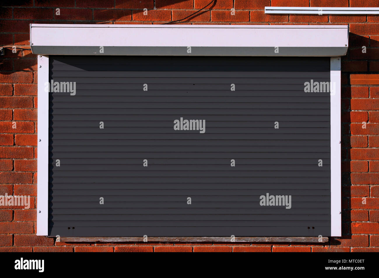 Closed black serving hatch security shutters with brick background ...
