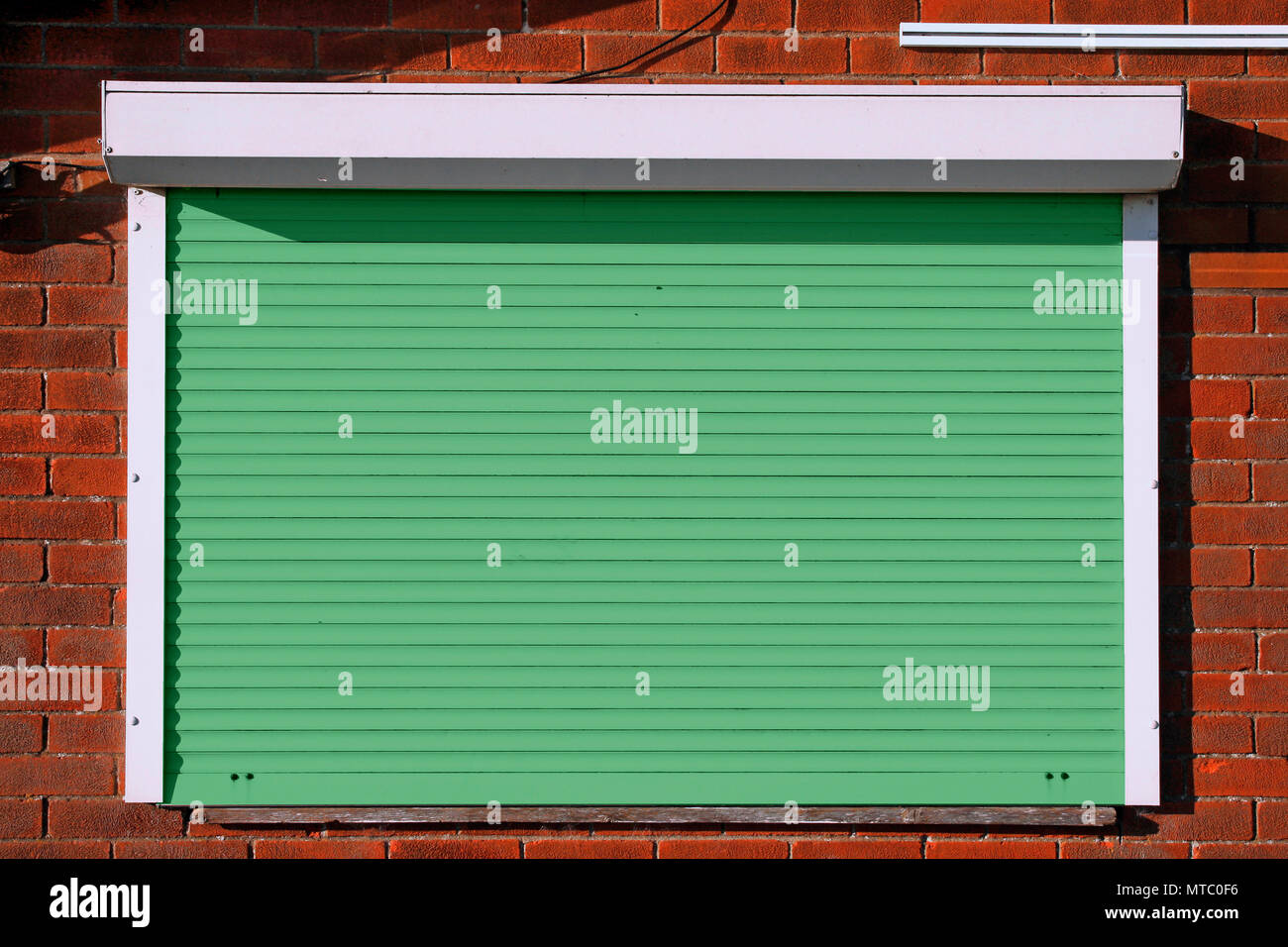 Closed green serving hatch security shutters with brick background ...