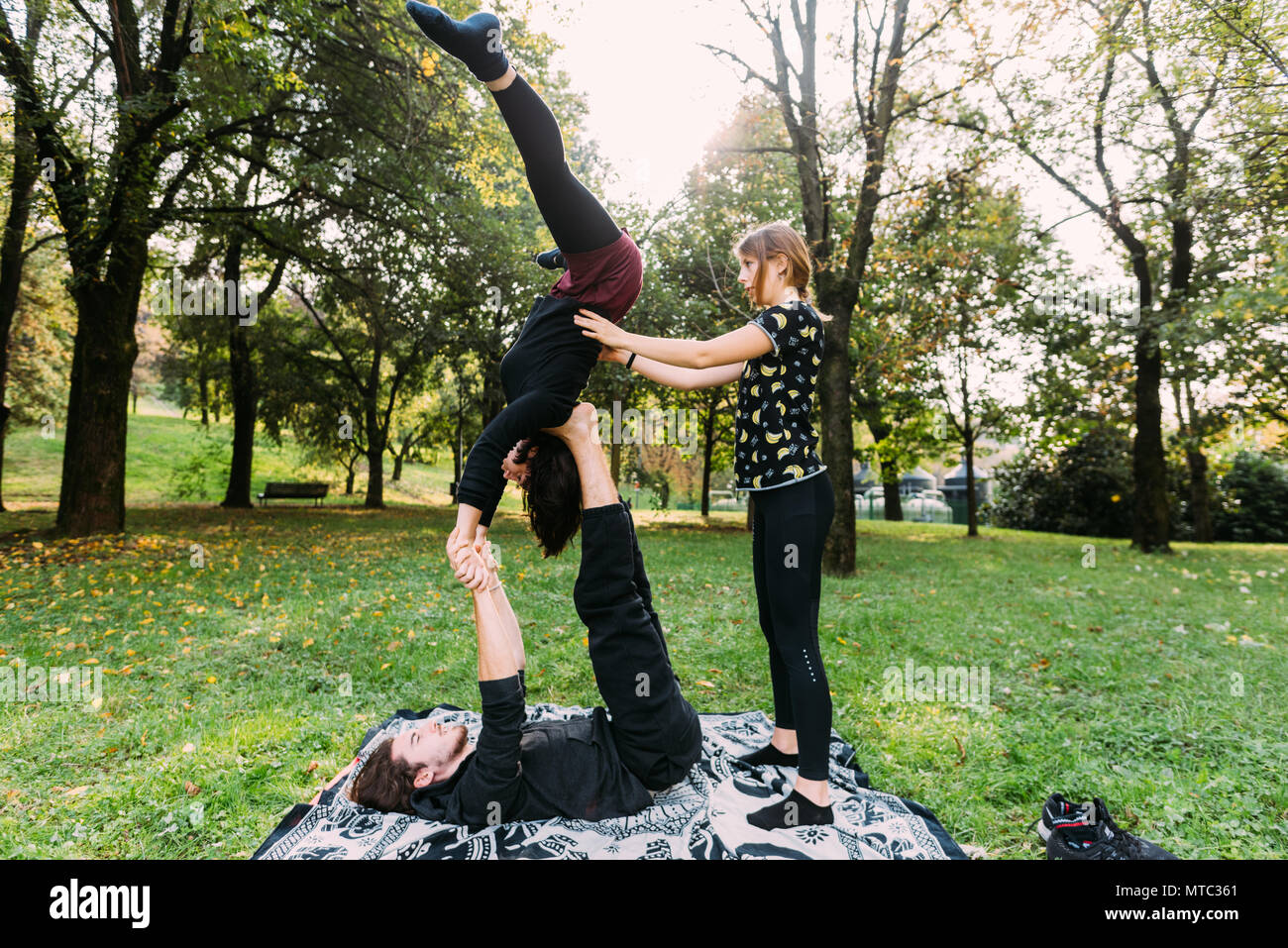 young woman teaching two people outdoor in a park - personal trainer ...