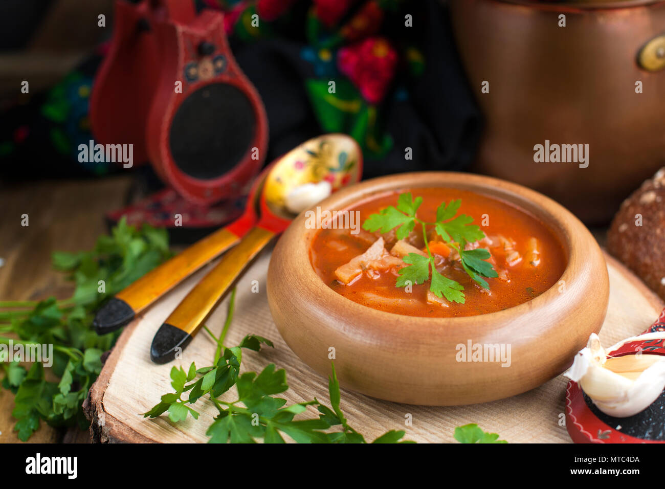 Traditional Ukrainian beet soup borscht in wooden bowl with garlic buns ...