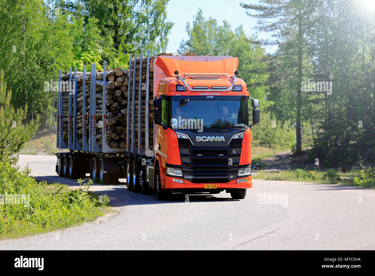 Orange Scania R650 logging truck on test drive on rural road through ...
