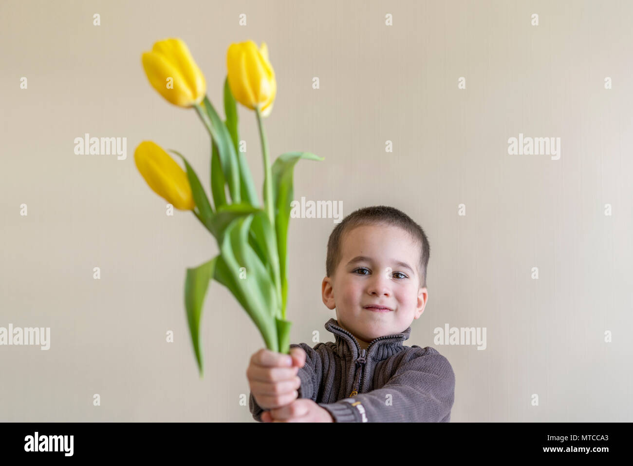 Little boy with a bouquet of yellow flowers. Boy hiding flower on his ...