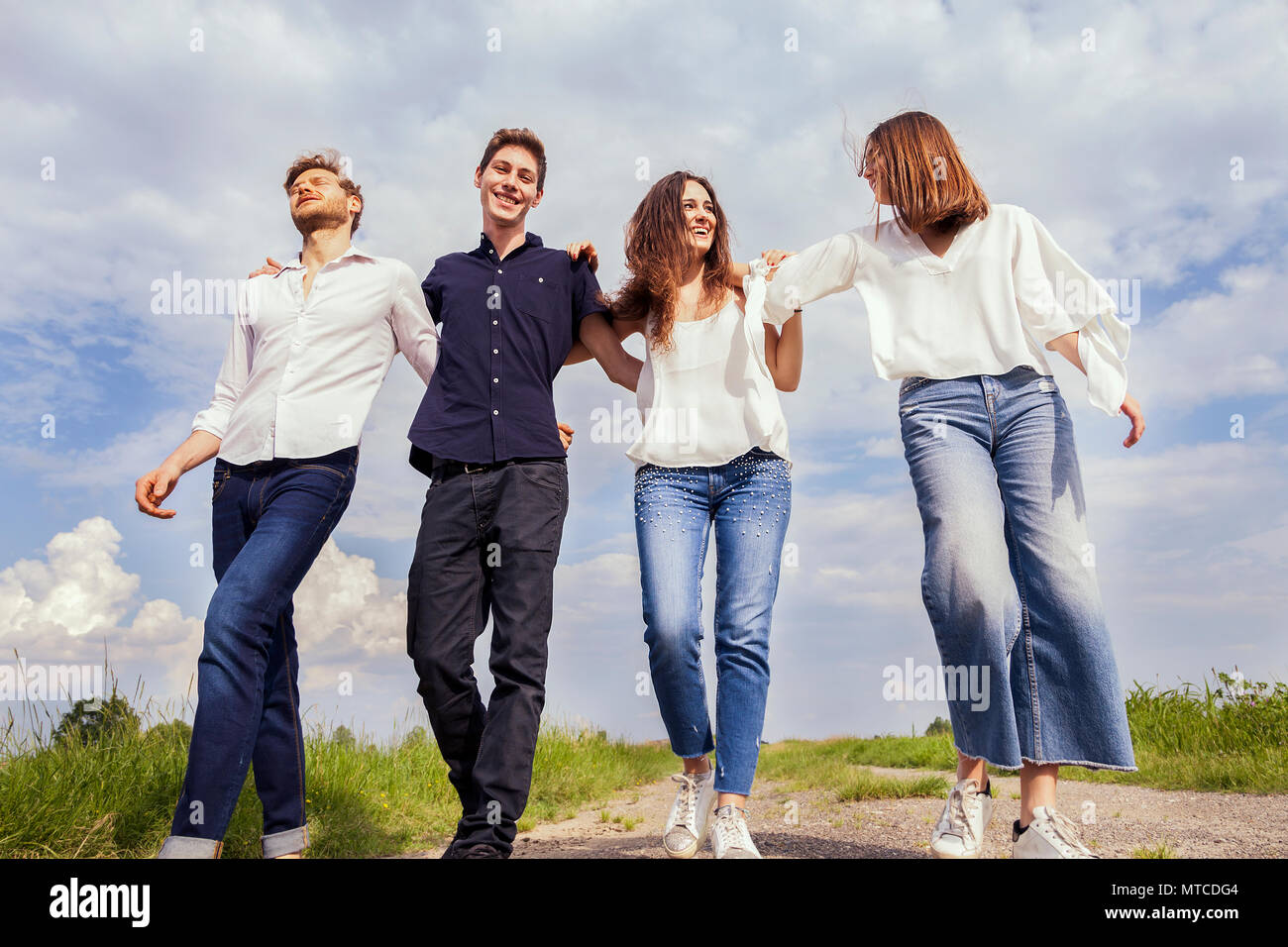 group of young handsome people walk together laughing on a country road ...