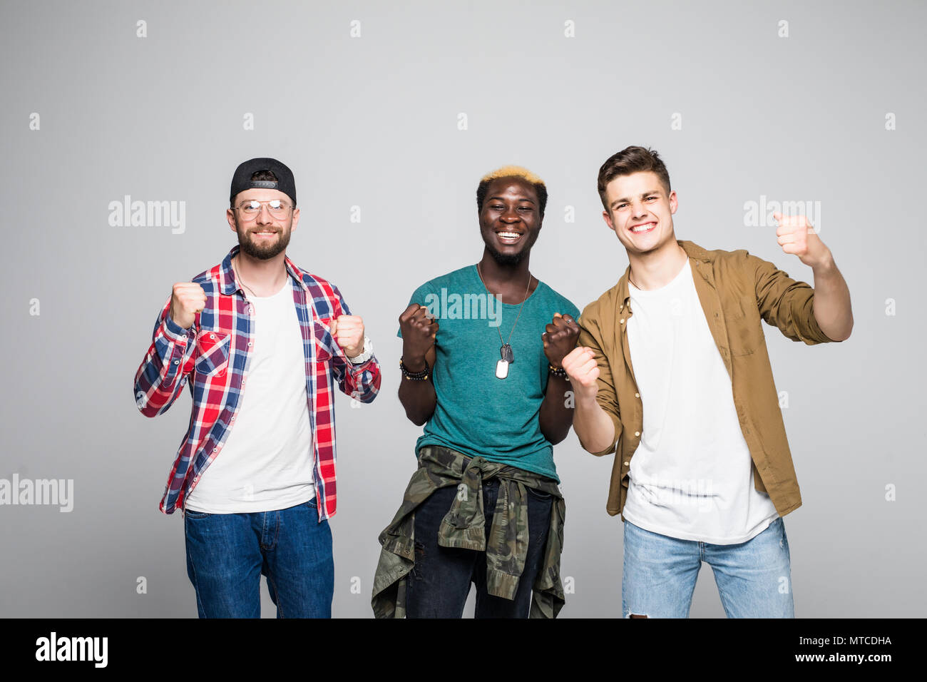 Three young cheery men football fans celebrating isolated over yellow ...