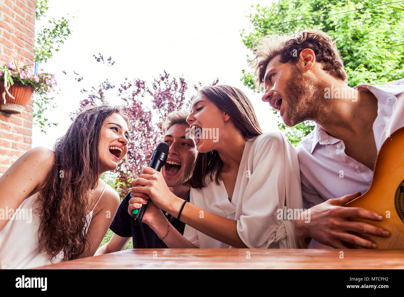 group of young friends having fun singing a song in the courtyard of a ...