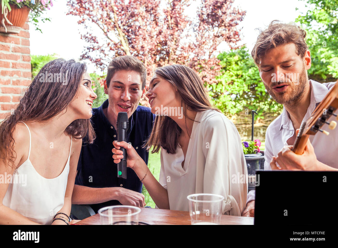 group of young friends having fun singing a song in the courtyard of a ...