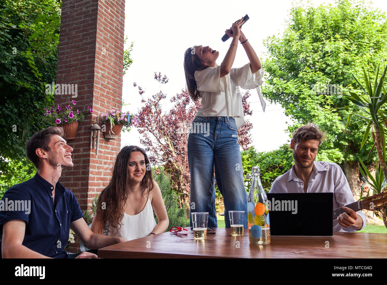 group of young friends having fun singing a song in the courtyard of a ...