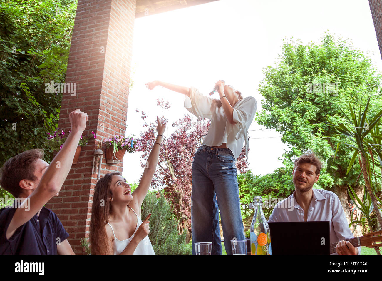 group of young friends having fun singing a song in the courtyard of a ...
