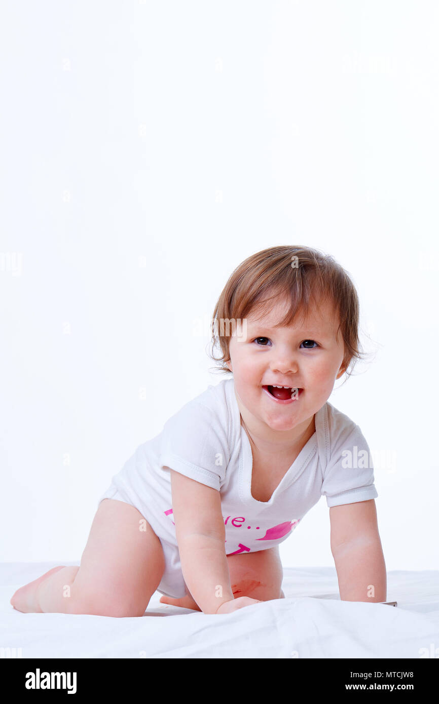 Cute baby girl inwhite body, crawling, laughing and playing at studio ...