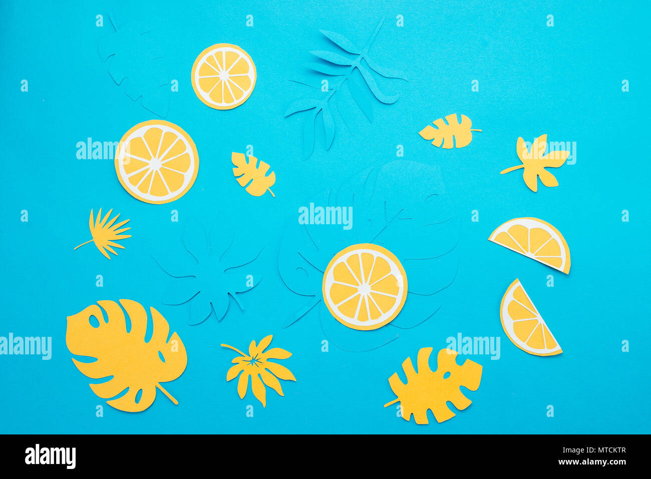 Lemon slices and tropical leaves pattern on a bright blue background ...