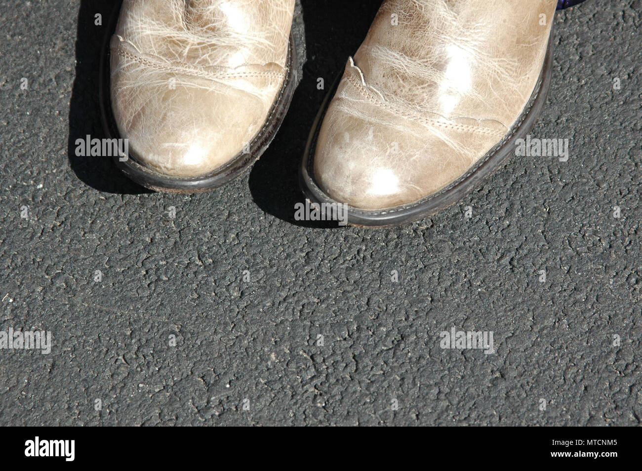 Closeup of the toes of a pair of menâ€™s brown boots on black concrete ...