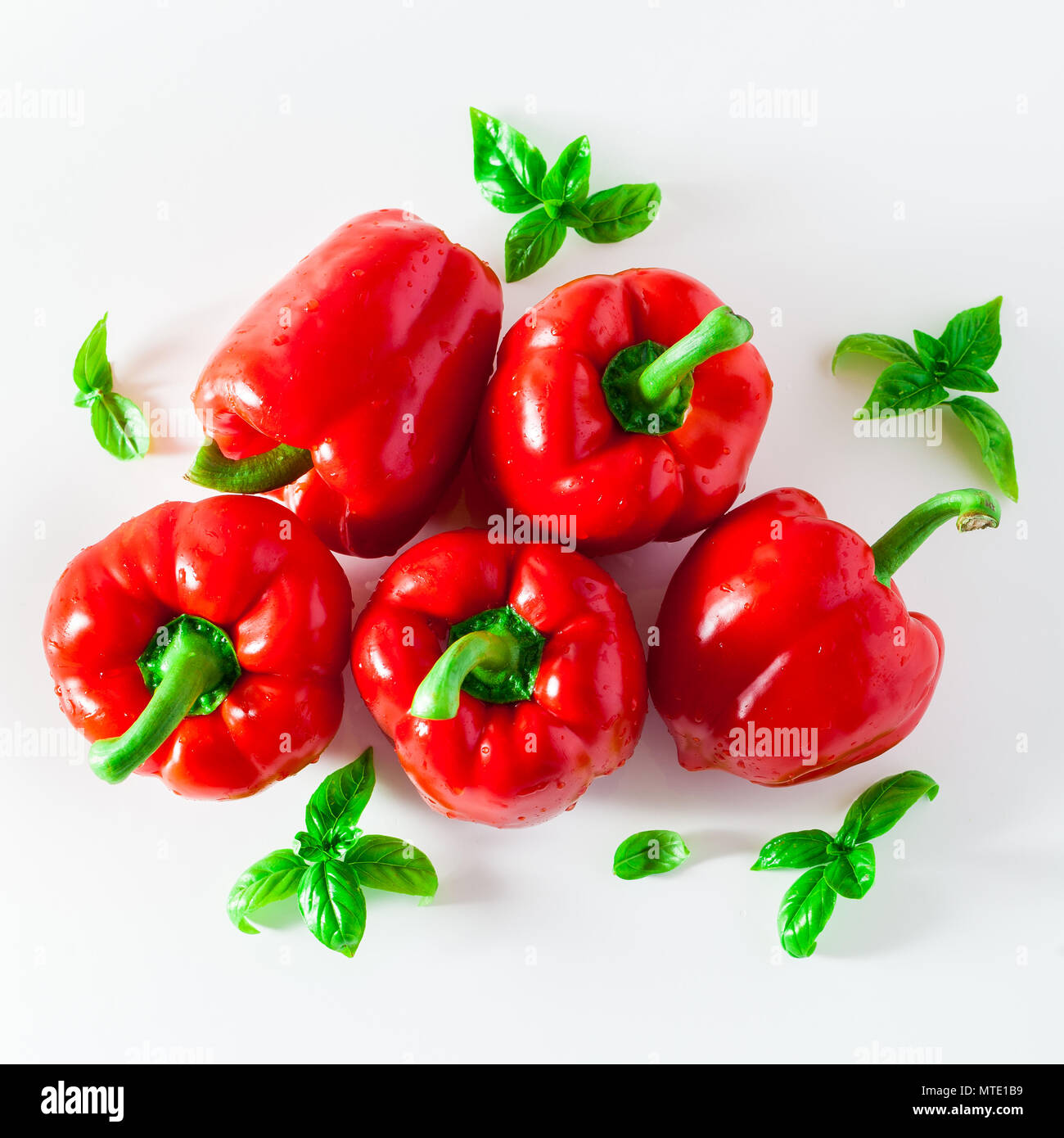 group of red ripe organic bell pepper and fresh basil leaves isolated ...