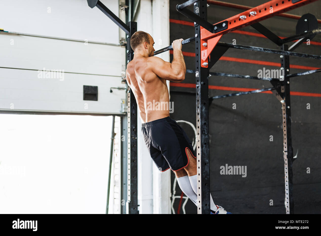 Young bodybuilder doing pull-up workout in gym Stock Photo - Alamy