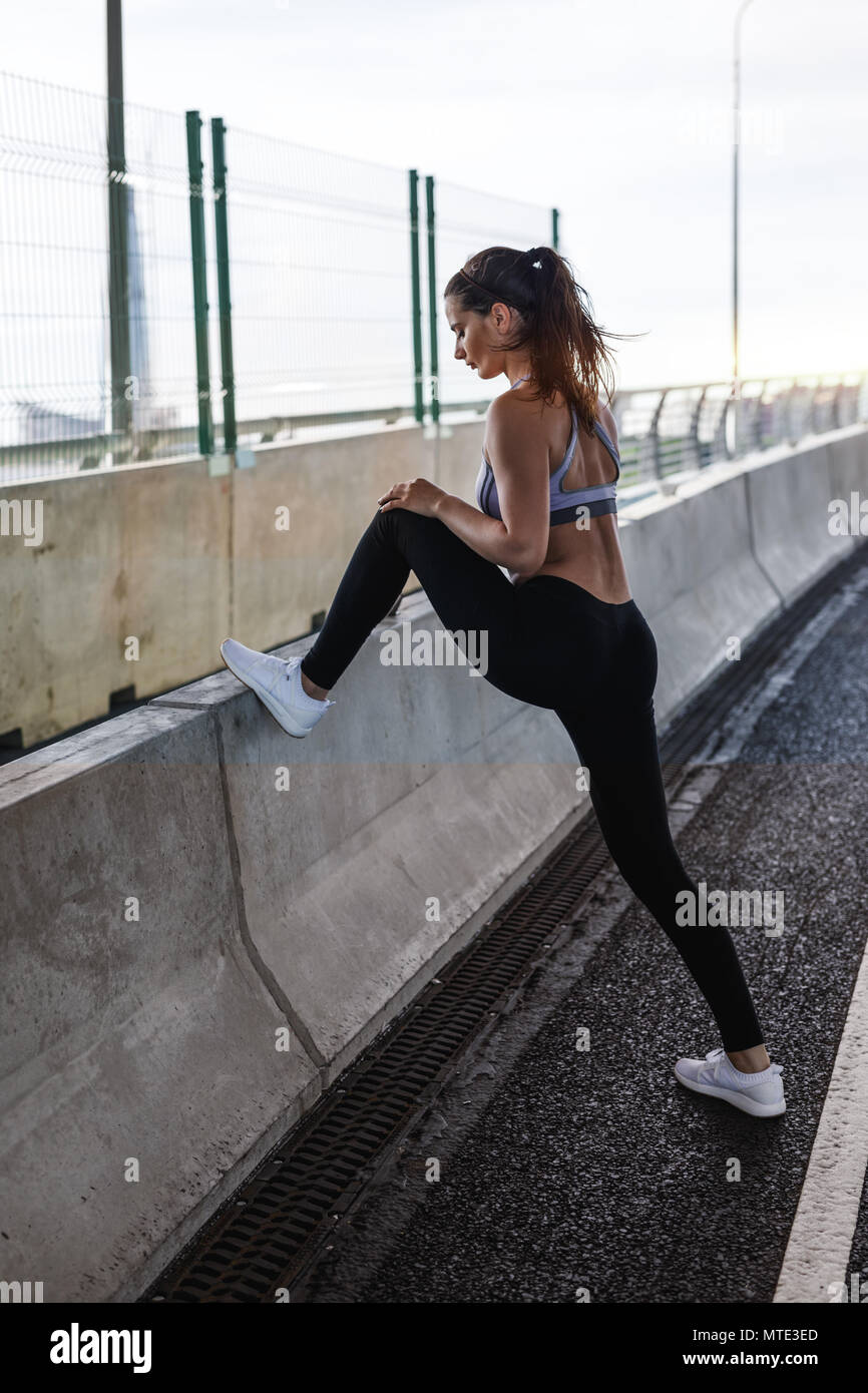 Outdoors workout. Side view of female jogger stretching legs Stock ...