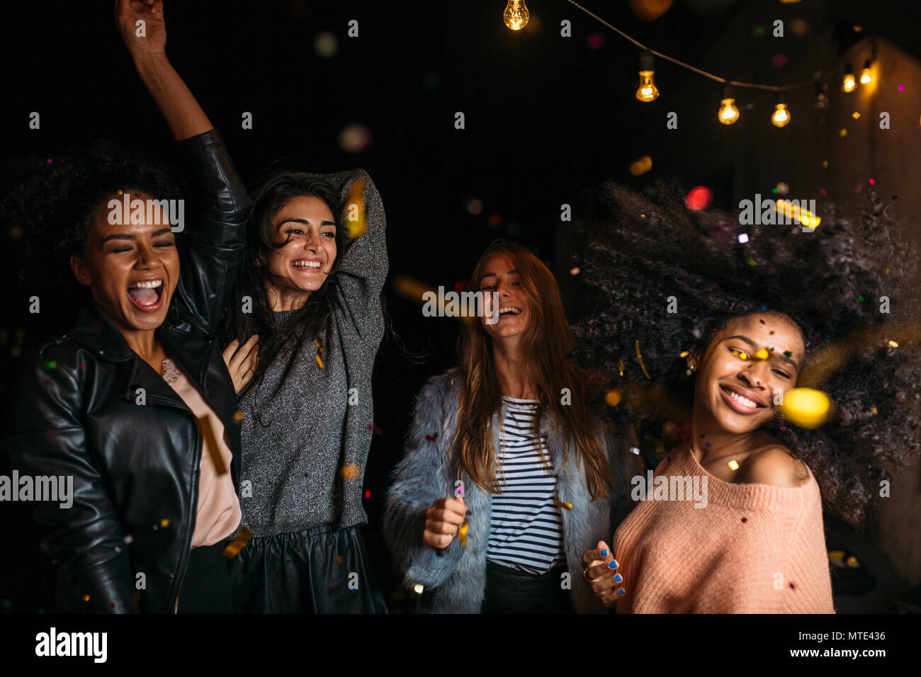 Young women at a party having fun with confetti Friends dancing ...