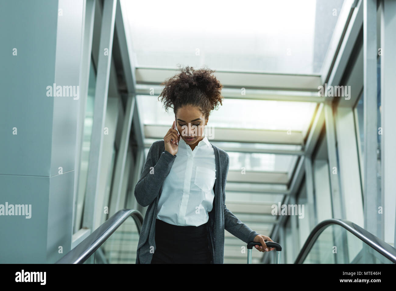 Woman making phone call while lifting up on escalator Stock Photo - Alamy