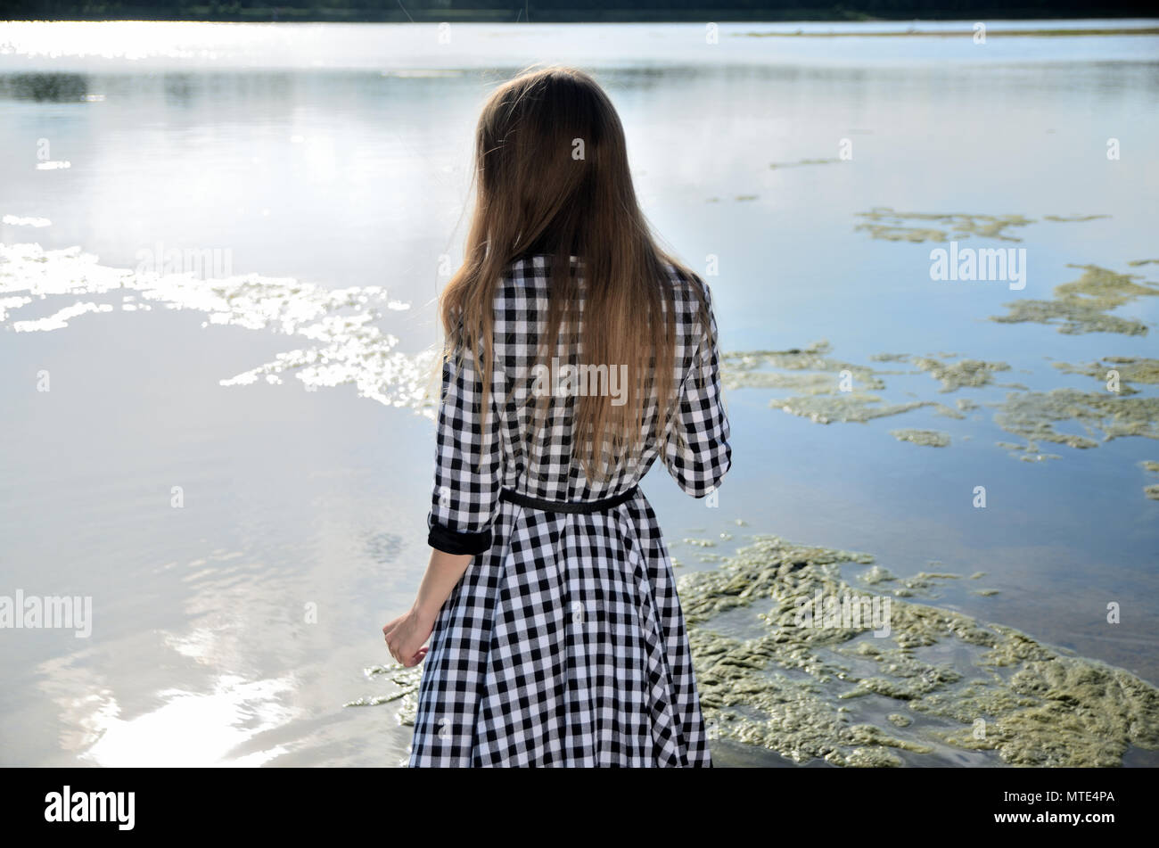 Female model stands in the water. Woman wears dress with black and ...