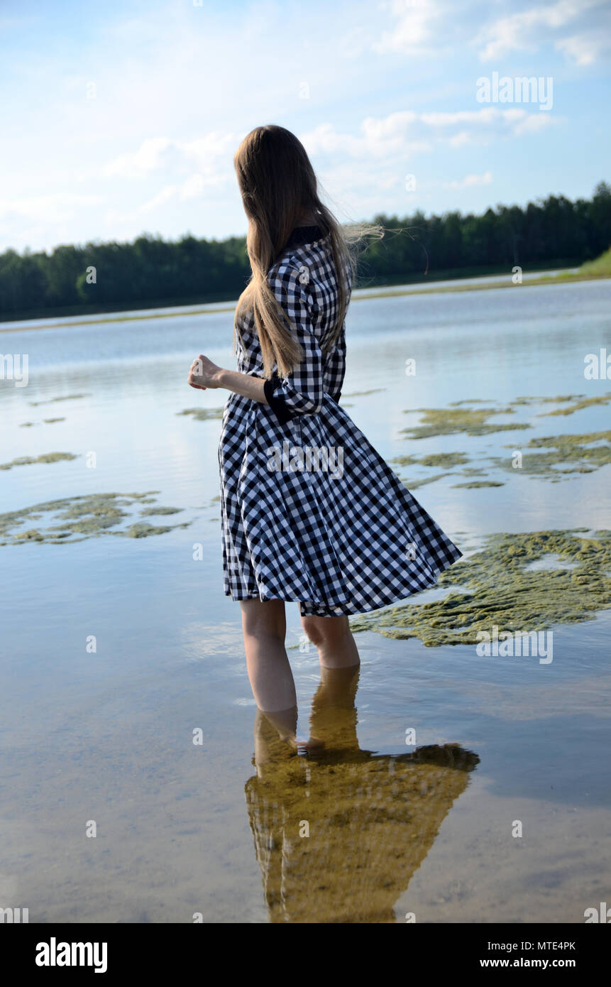 Female model stands in the water. Woman wears dress with black and ...