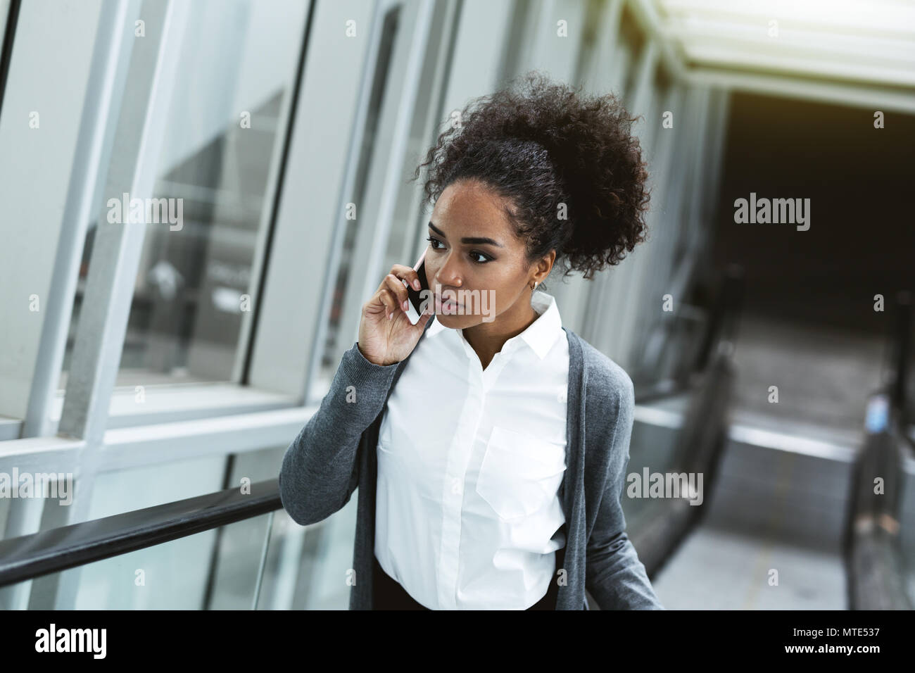 Woman making phone call while lifting up on escalator Stock Photo - Alamy