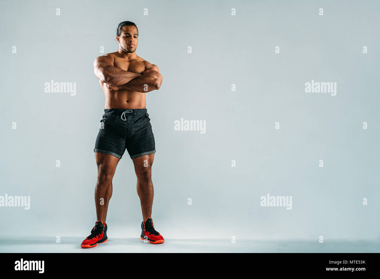 Studio shot of young bodybuilder standing over gray background, wearing ...