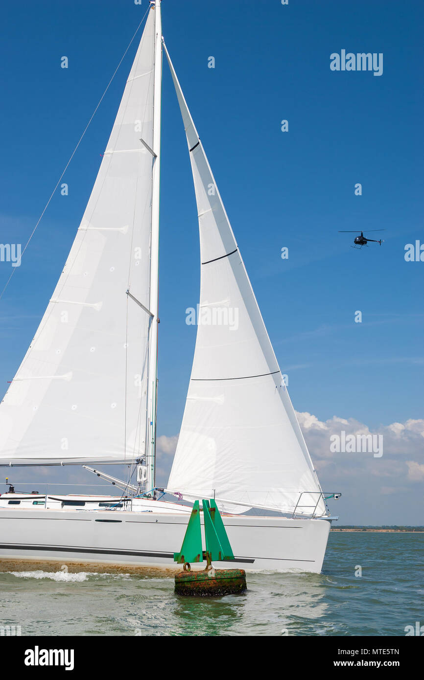 Sailing boat, sail boat or yacht with white sails passing a green ...