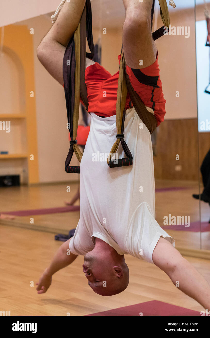 Anti-gravity Yoga, man doing yoga exercises. the man is hanging upside ...