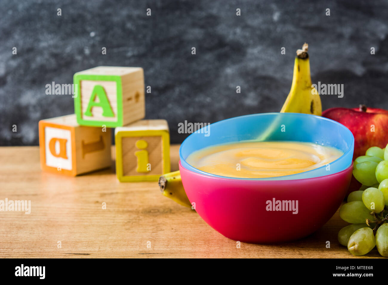Baby food: colorful bowl of fruit puree on wooden table. Copyspace ...