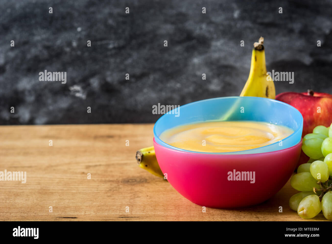 Baby food: colorful bowl of fruit puree on wooden table. Copyspace ...
