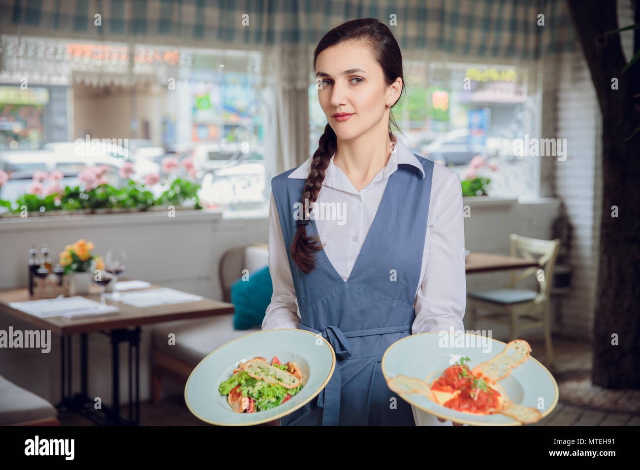 Waitress is carrying two plates with restautant delicious dishes ...