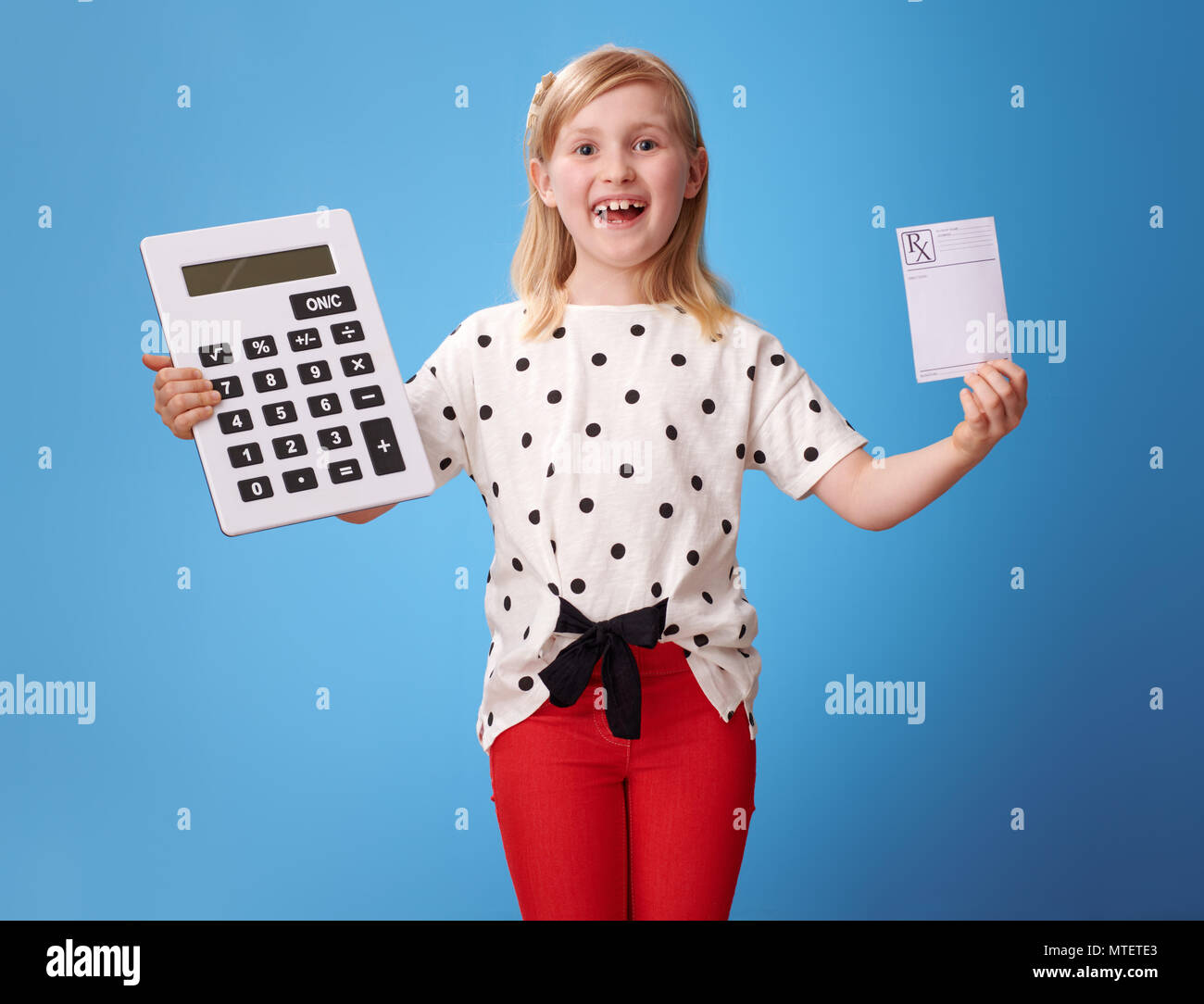 smiling modern child in red pants showing prescription and calculator ...