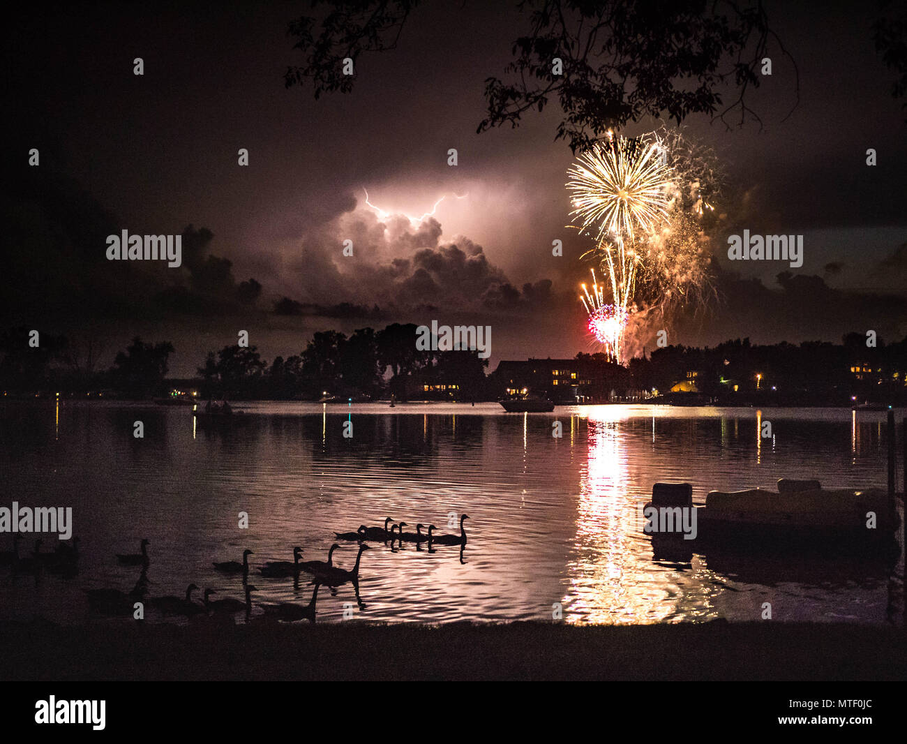 Fireworks exploding in the distance with a lightning storm happening ...