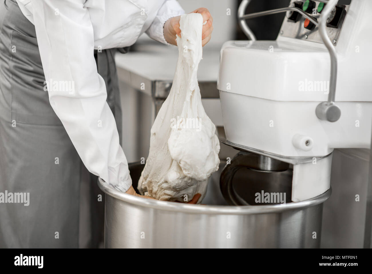 Woman mixing dough with professional kneader machine at the ...