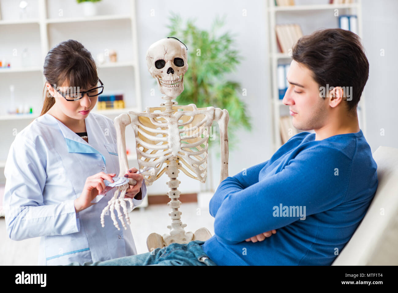 Doctor showing type of injury on skeleton to patient Stock Photo - Alamy