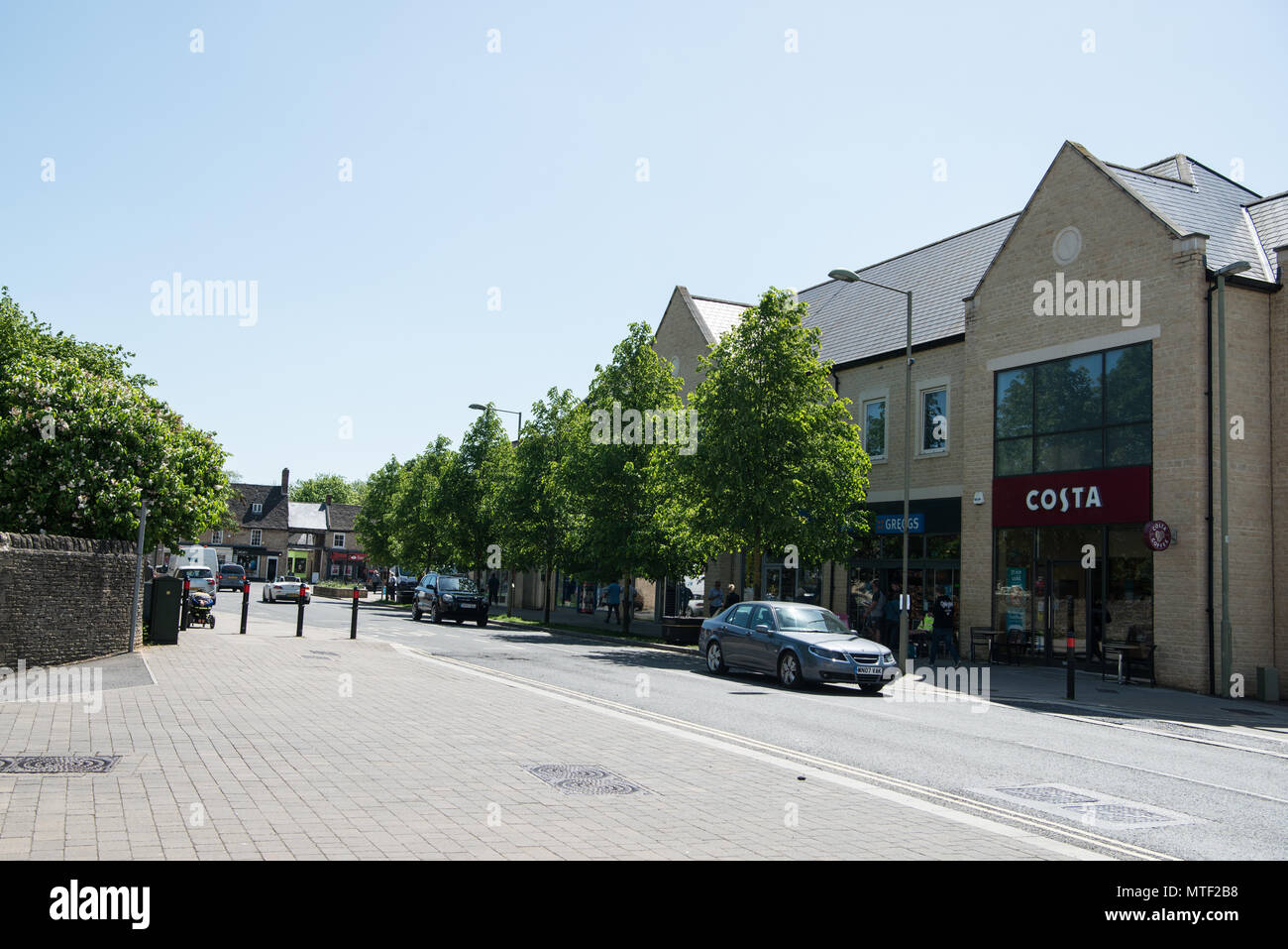 high street shops with Costa coffee in focus. Road with trees and ...
