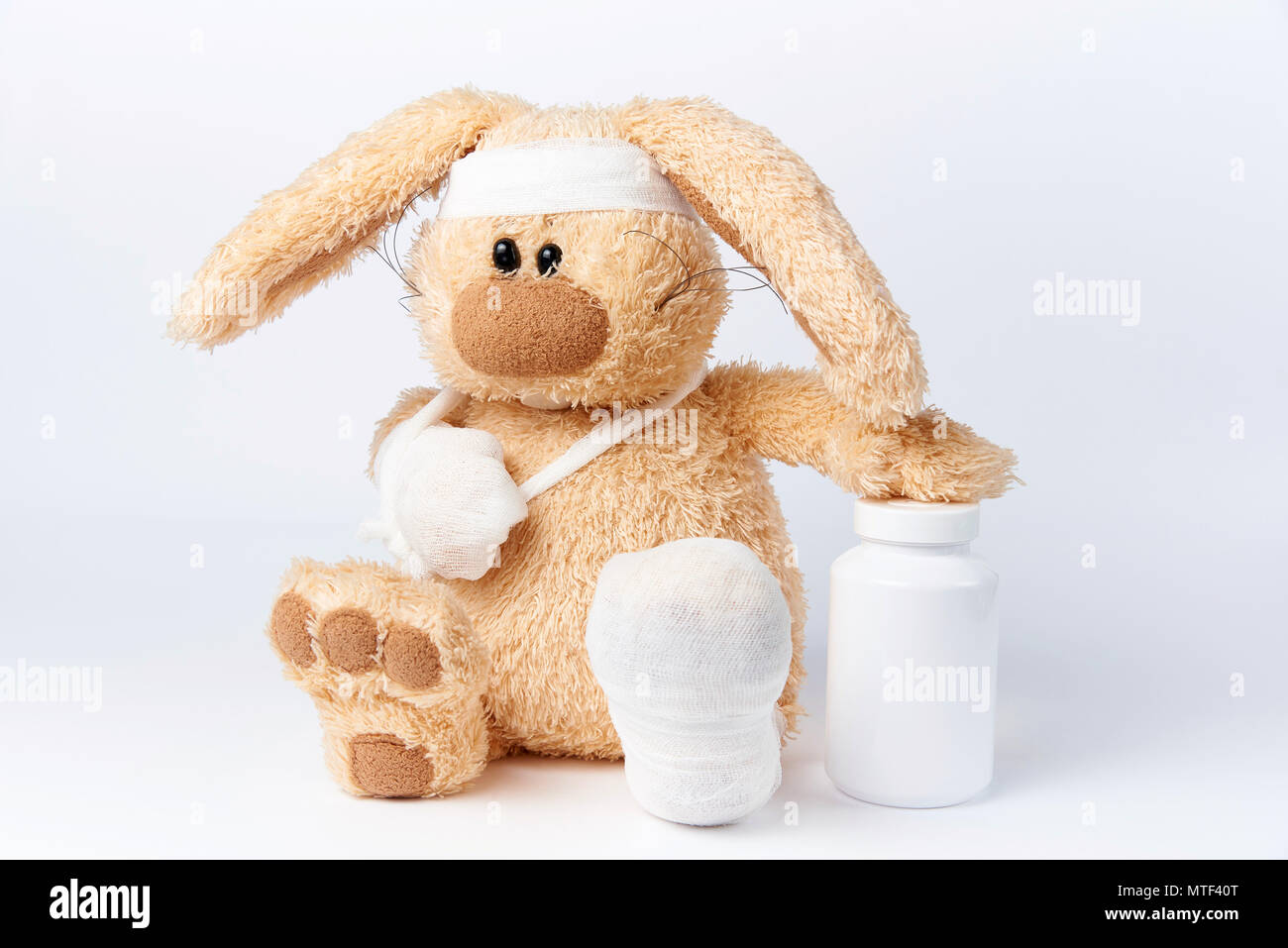 Cute sick bandaged hare with a jar of medicines on a white background ...