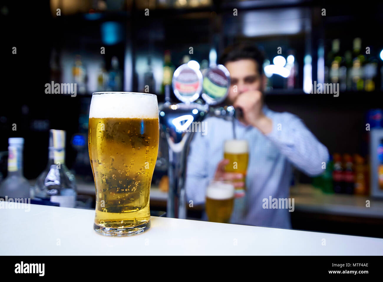 A glass of beer on a blurry bar background Stock Photo - Alamy