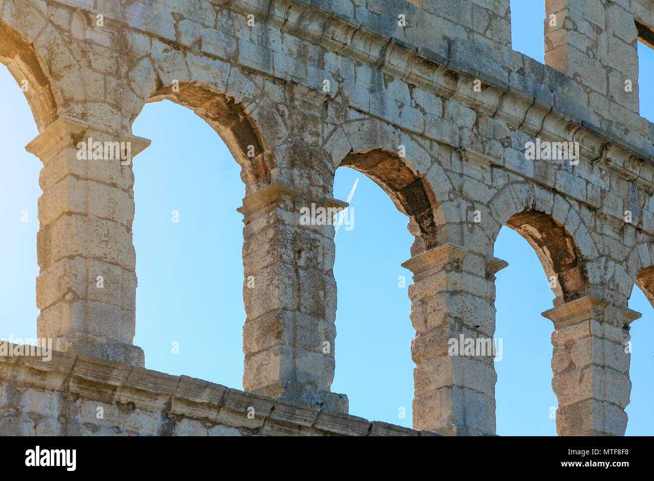 Arched windows of an ancient Roman amphitheater against the blue sky ...