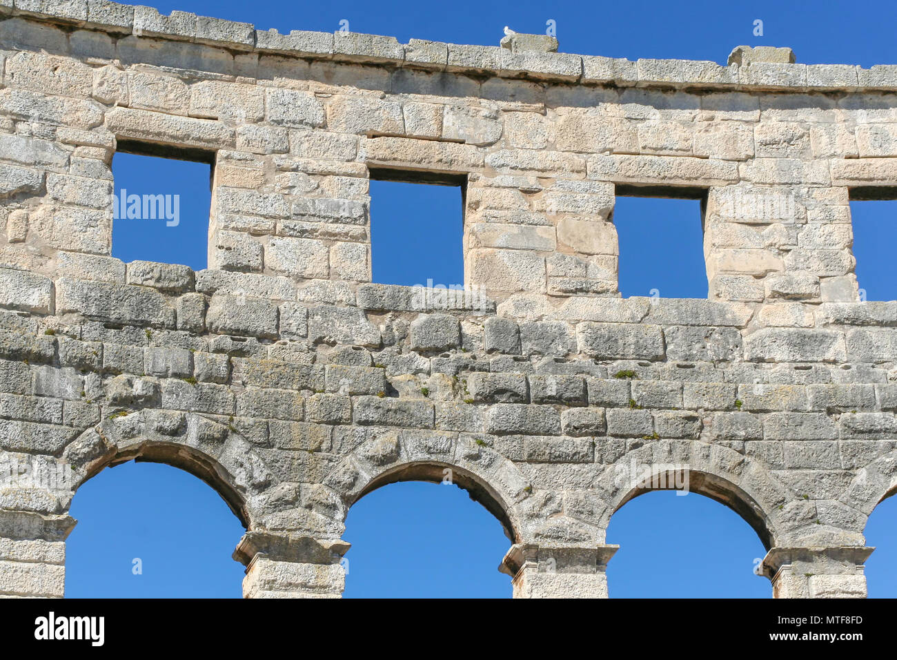 Wall of an ancient Roman amphitheater with arched windows on background ...