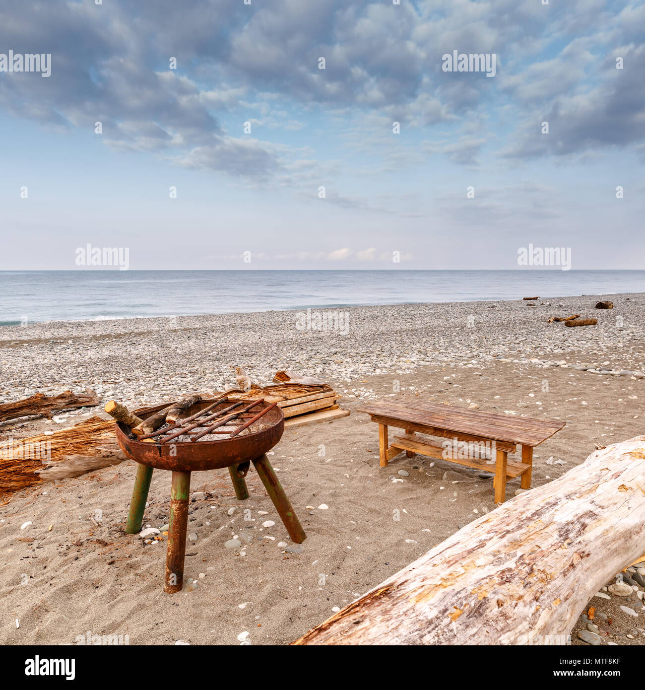 Metal brazier for cooking a variety of food on fire is on the seashore ...