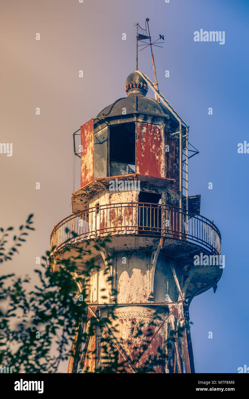 Dome of an old rusty metal lighthouse in the sun rays. Toned image ...