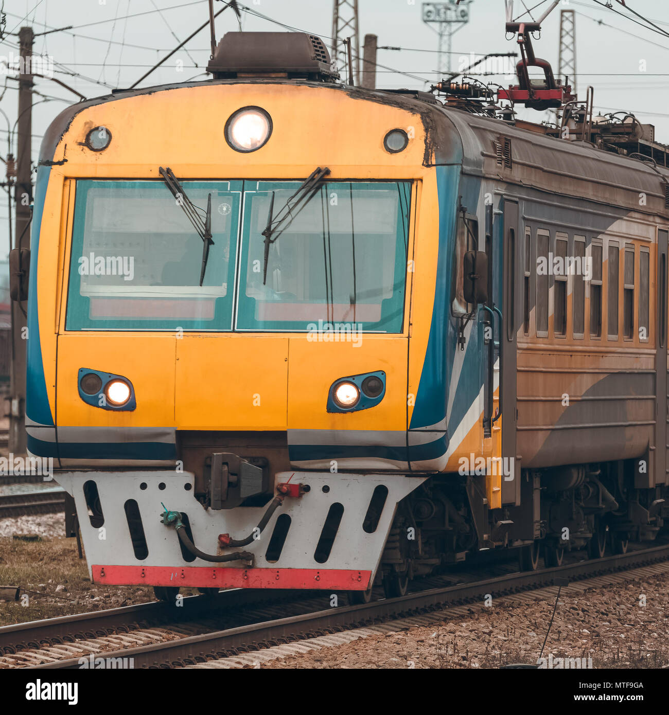Yellow modern passenger electric train moving at the old terminal Stock ...