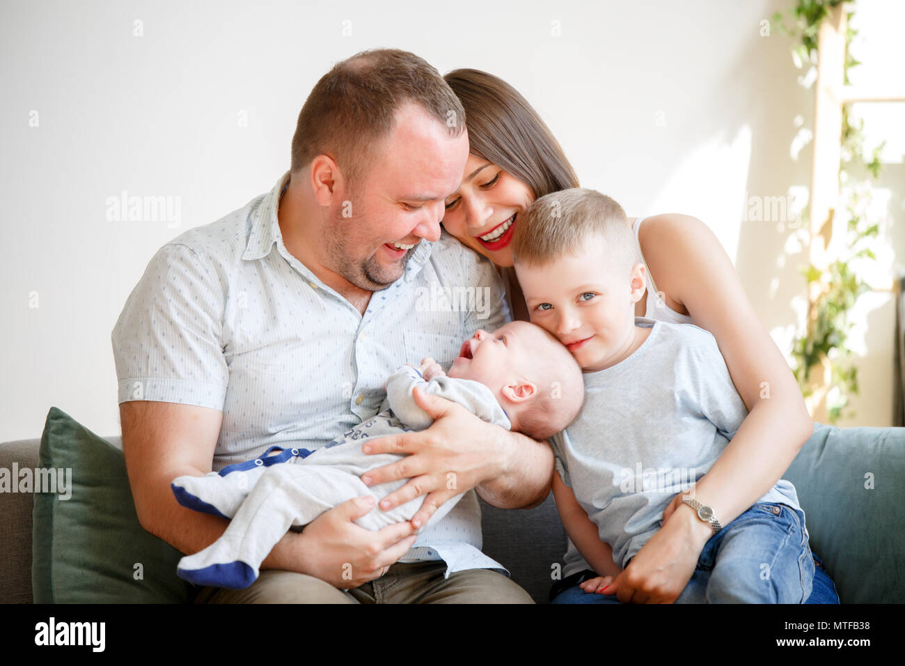 Image of happy parents with two sons on sofa in apartment Stock Photo ...