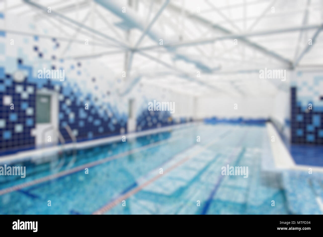 Modern indoor light swimming pool decorated with blue tiles. Blur ...