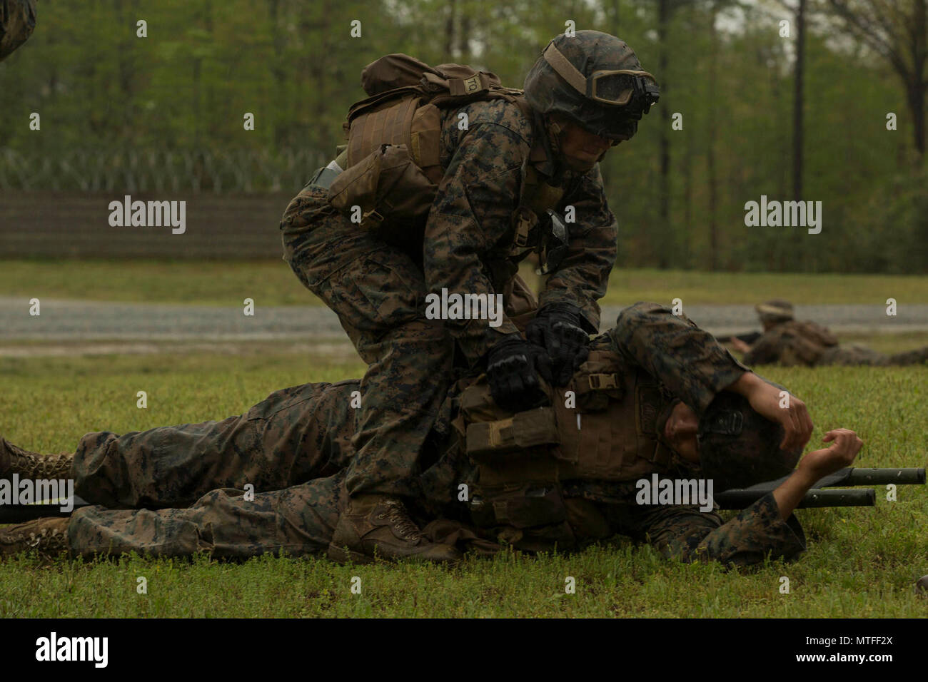 A Marine rolls a team member with feigned injuries onto a stretcher ...