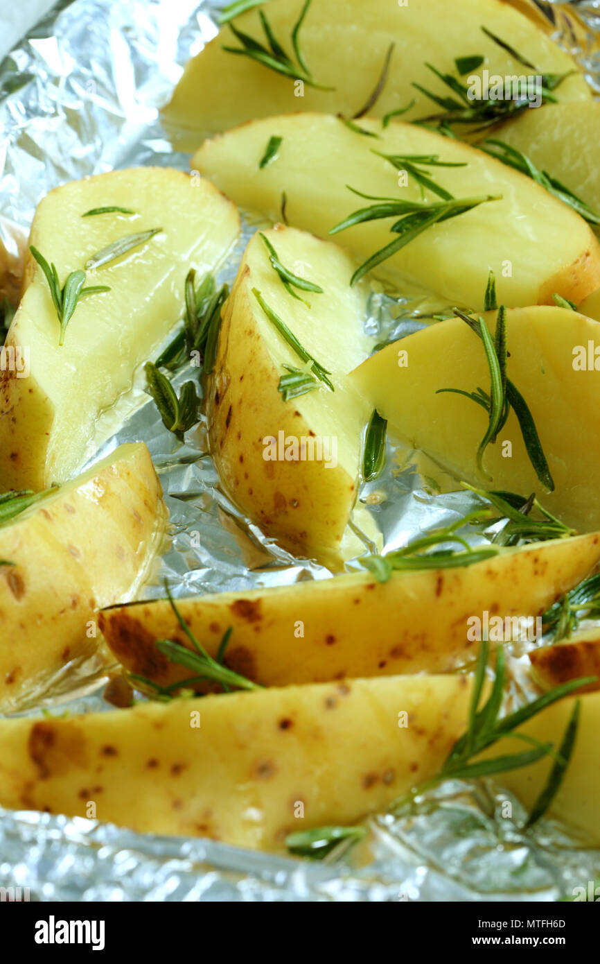 Raw potato wedges covered with rosemary on foil baking tray Stock Photo ...