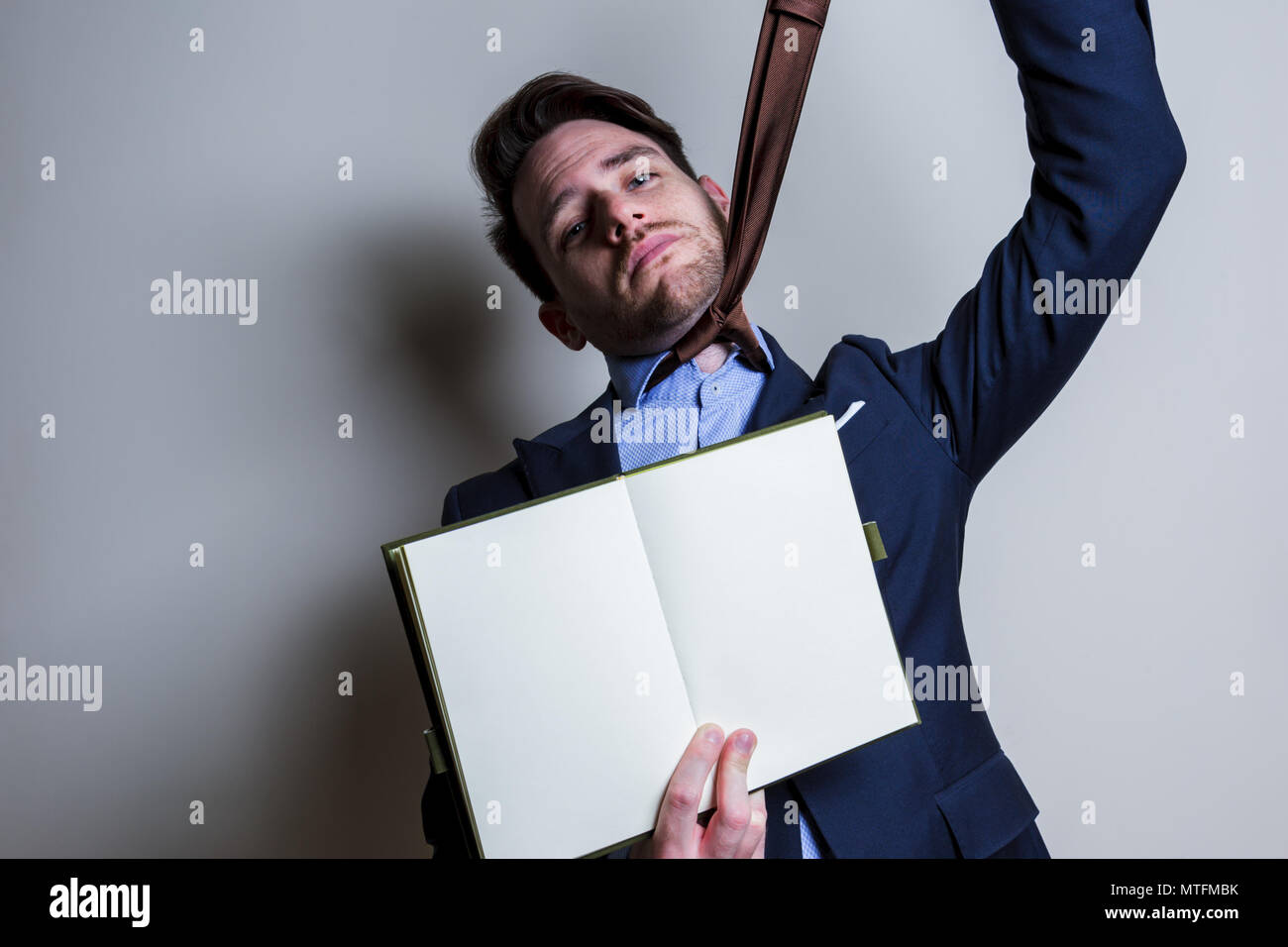 Worried business man hang up with his tie and show blank note. Studio ...