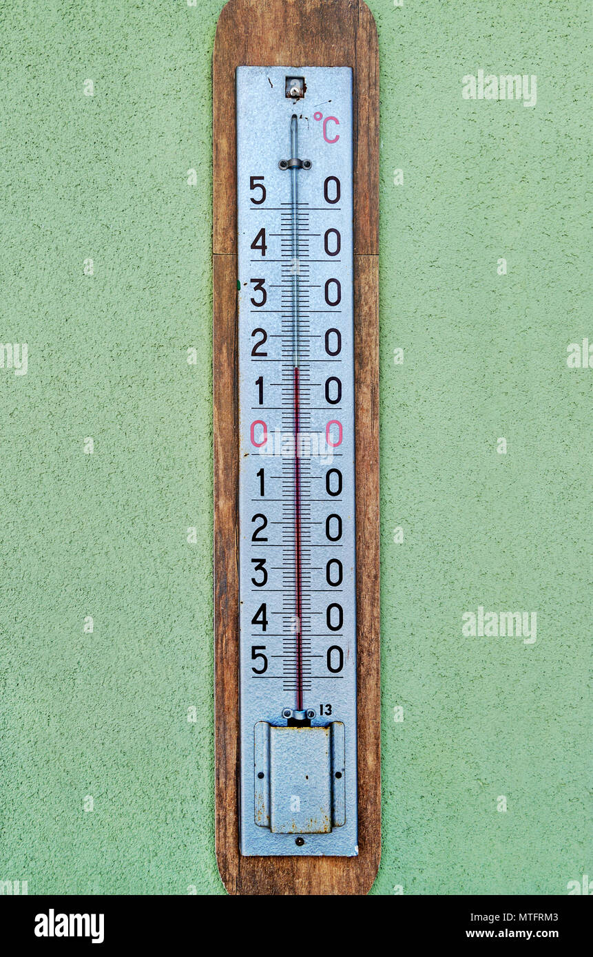 A classic street alcohol thermometer hanging on a plastered wall Stock ...
